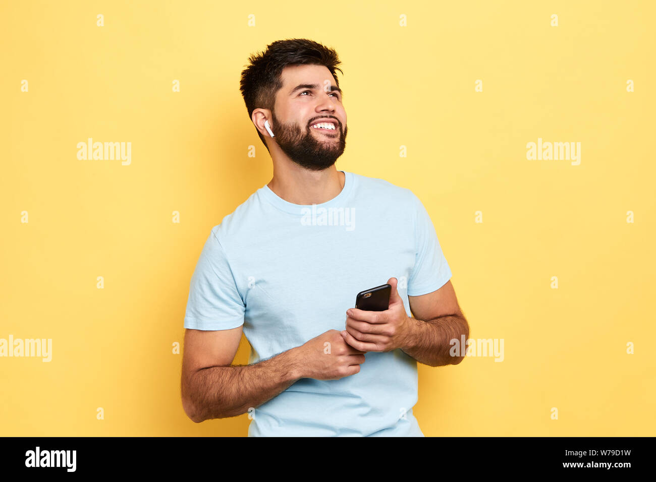 Excited cheerful man using smartphone, looking up, enjoying listening ...