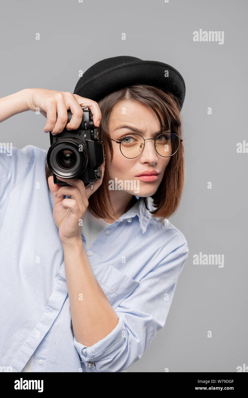 Young serious female photographer with camera concentrating on taking ...