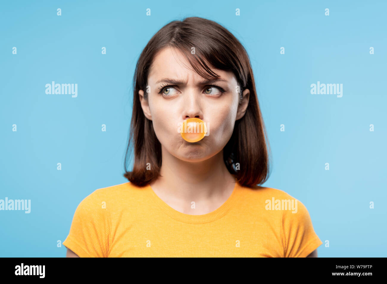 Brunette female teenager blowing bubble from yellow chewing-gum Stock ...