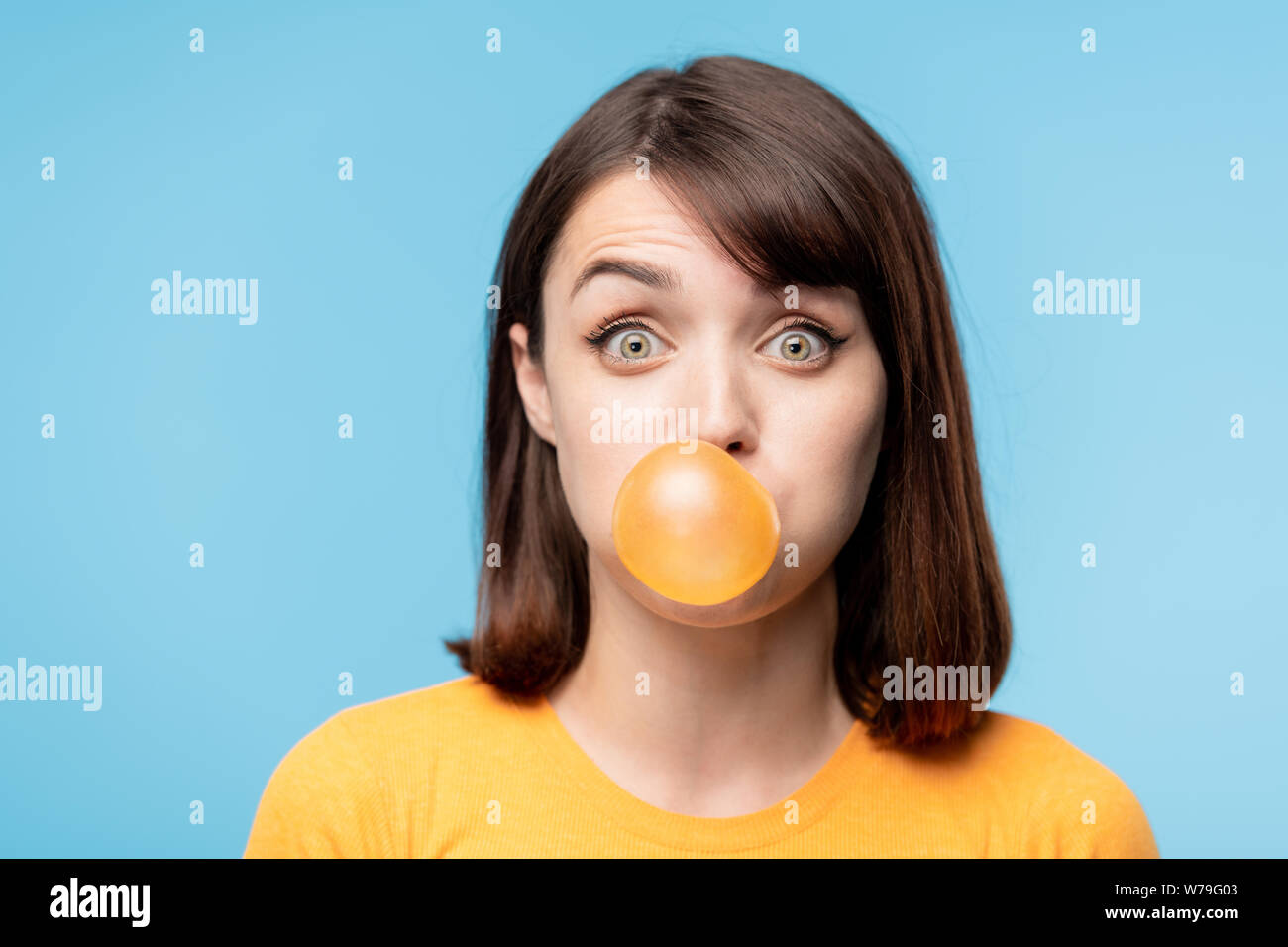 Young Amazed Brunette Staring At You While Blowing Chewing Gum Bubble