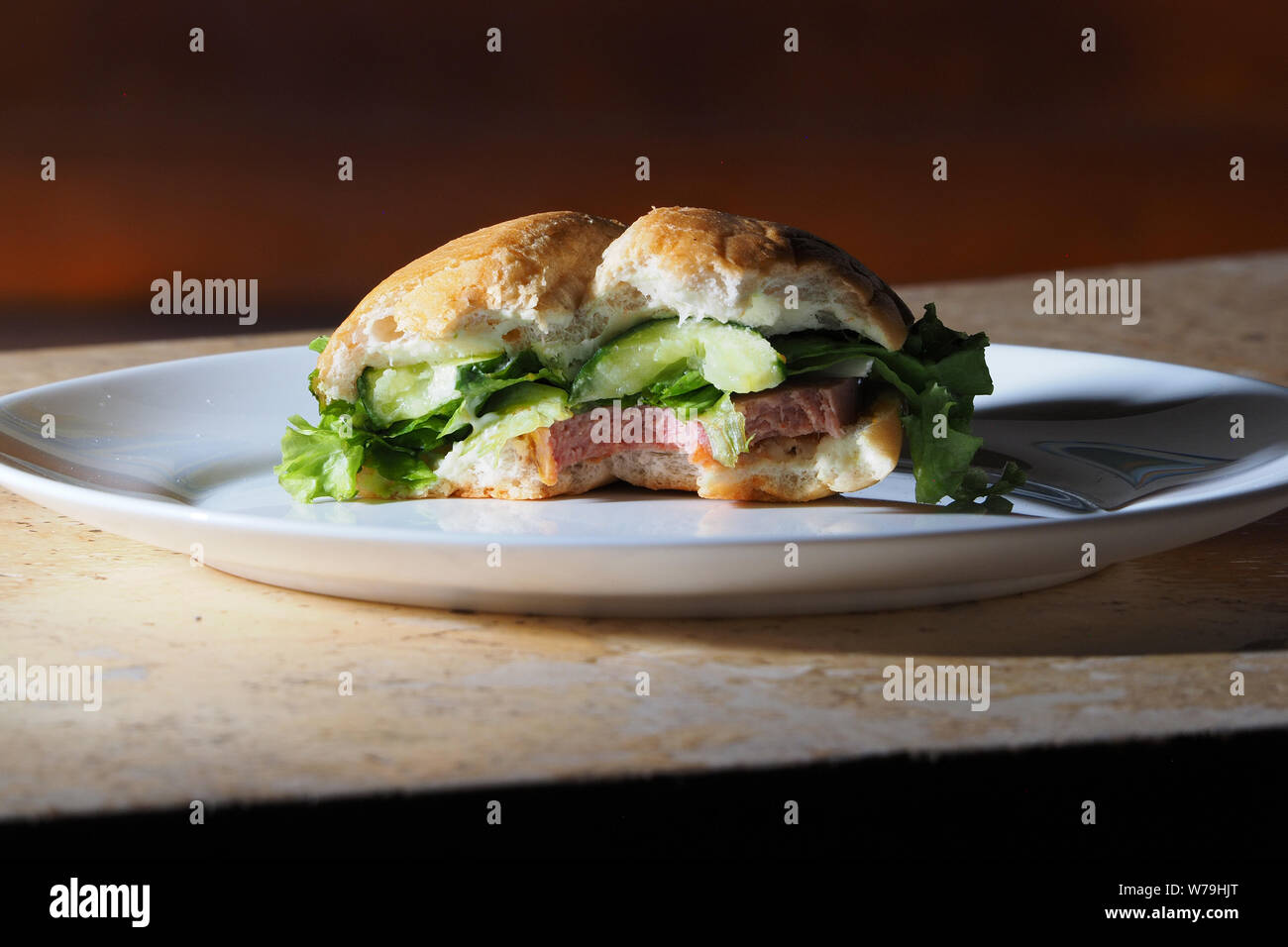 half-eaten sandwich in a plate on the table at night Stock Photo - Alamy
