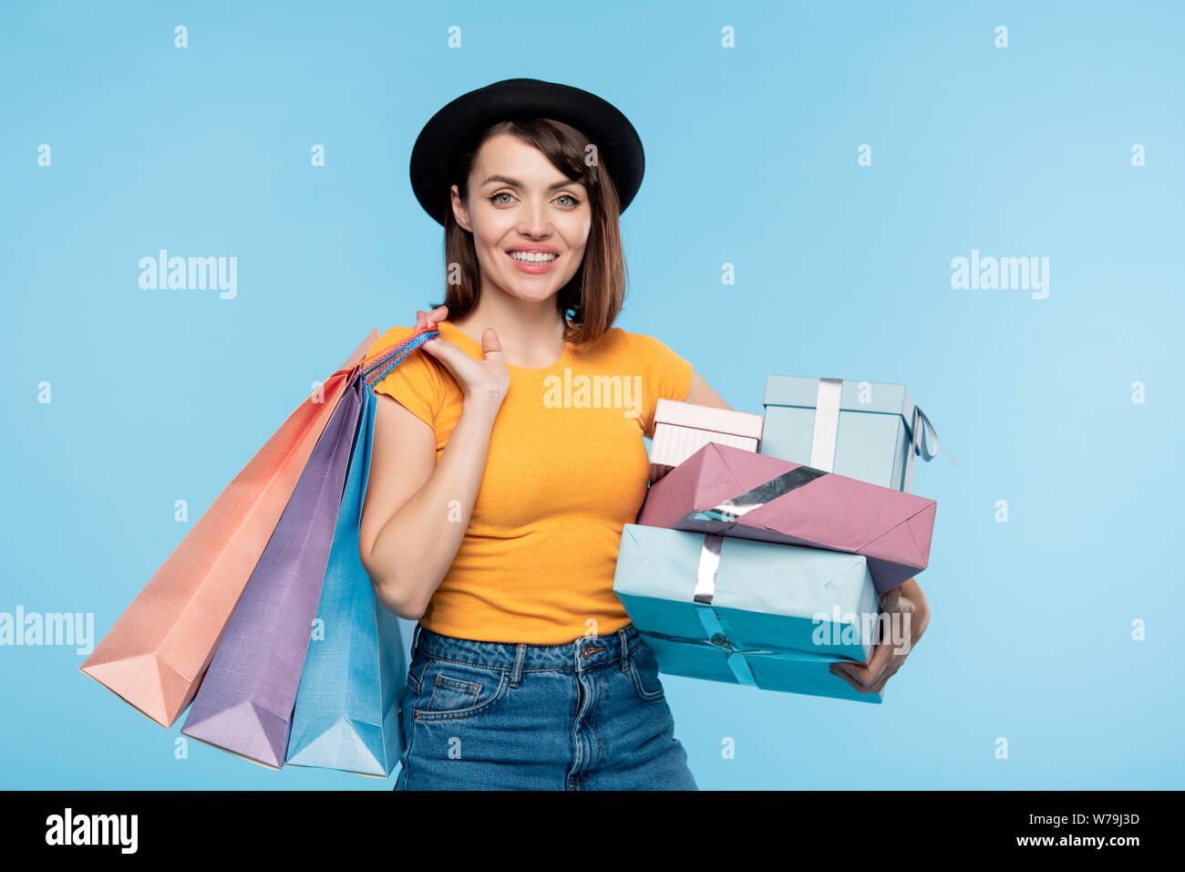 Cheerful and satisfied consumer carrying paperbags and stack of gifts ...