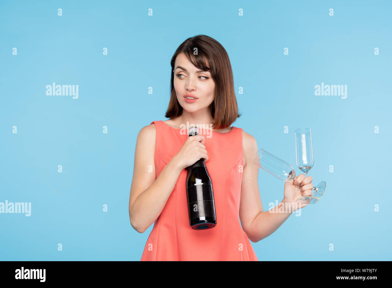 Young attractive sly woman with two glutes and bottle of champagne ...