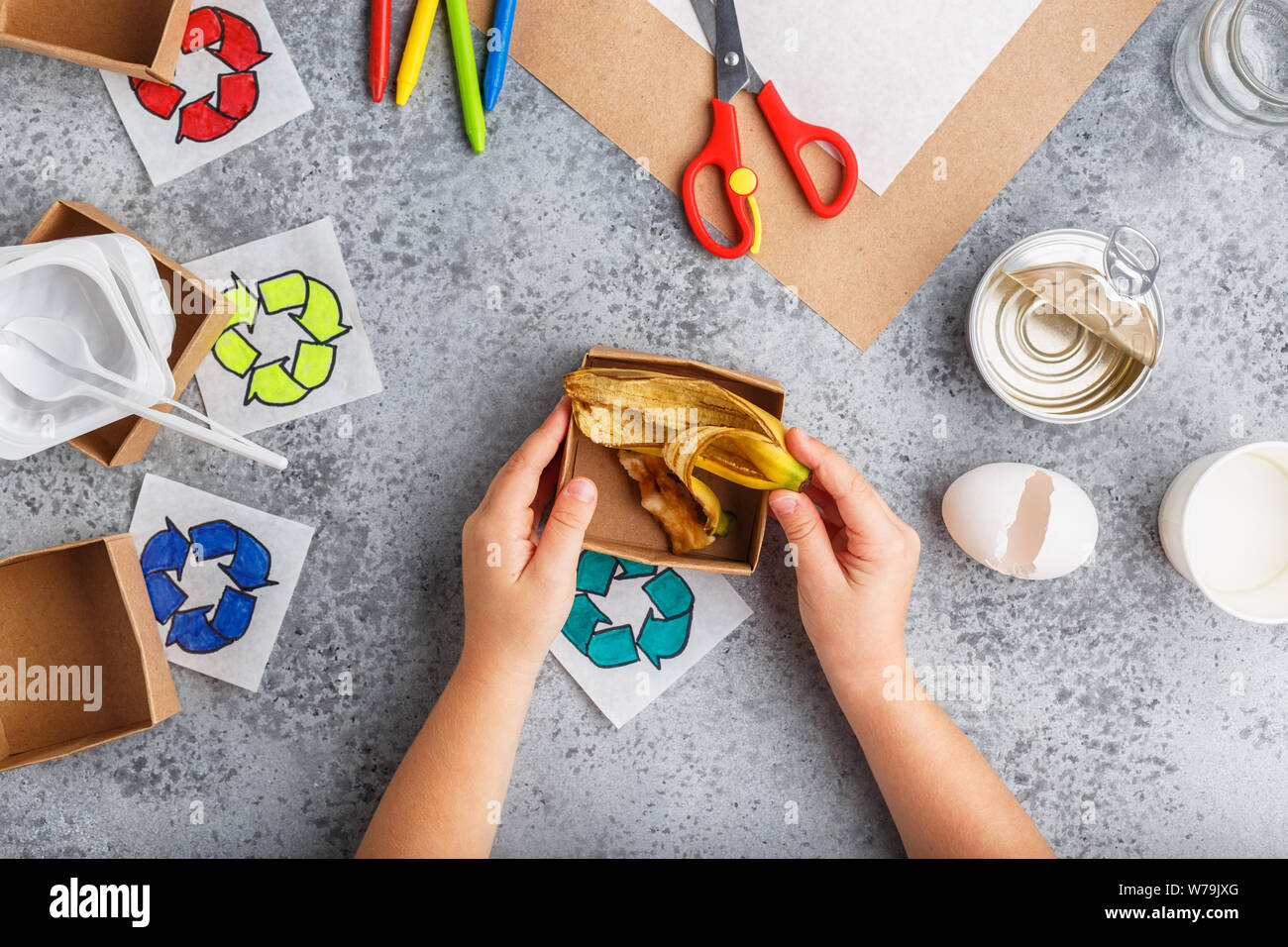 Girl hands are making recycling game in paper on grey background ...