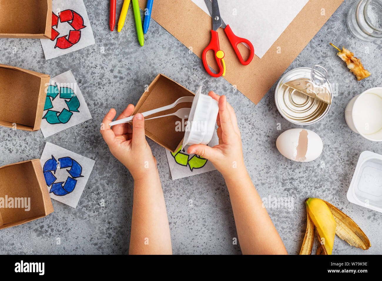 Girl hands are making recycling game in paper on grey background ...