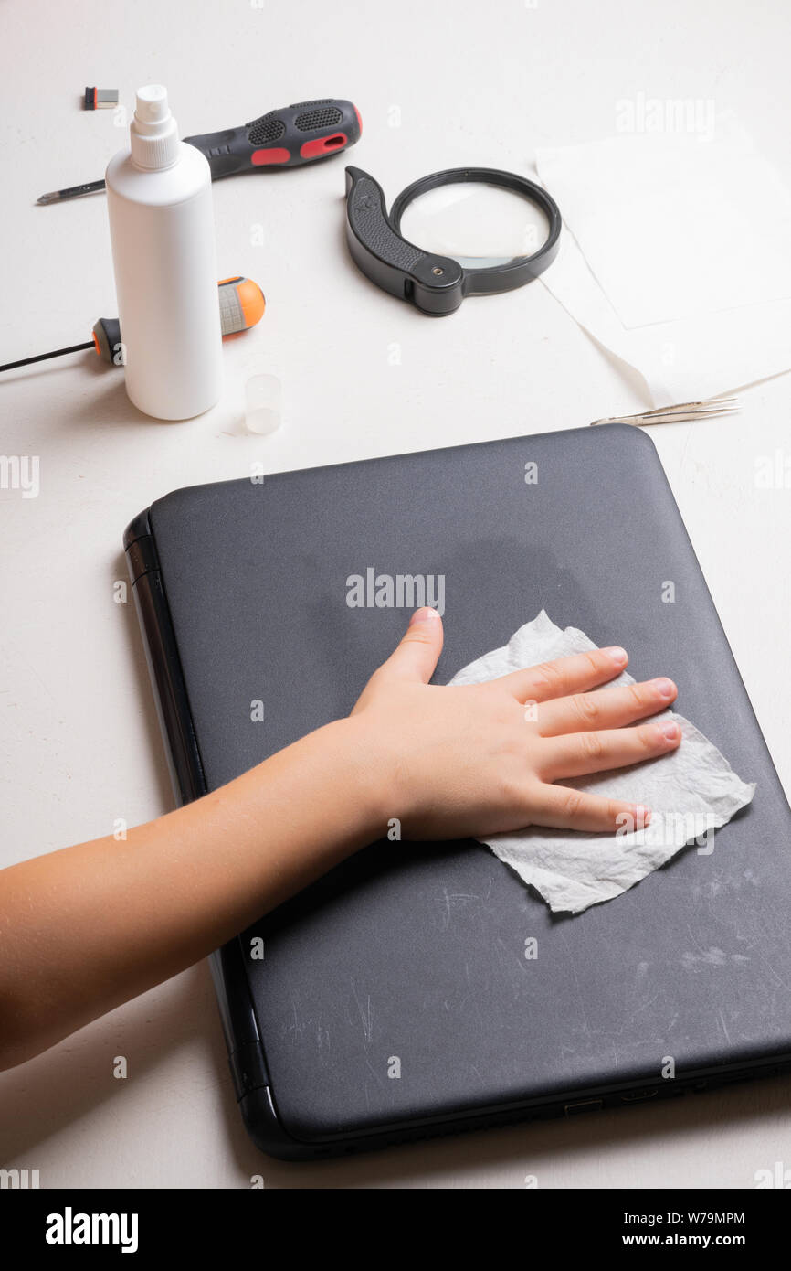 A teenager boy of 10 years old is cleaning his laptop with a special ...
