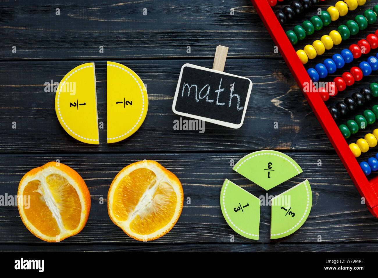 Сolorful math fractions and oranges as a sample on dark wooden ...