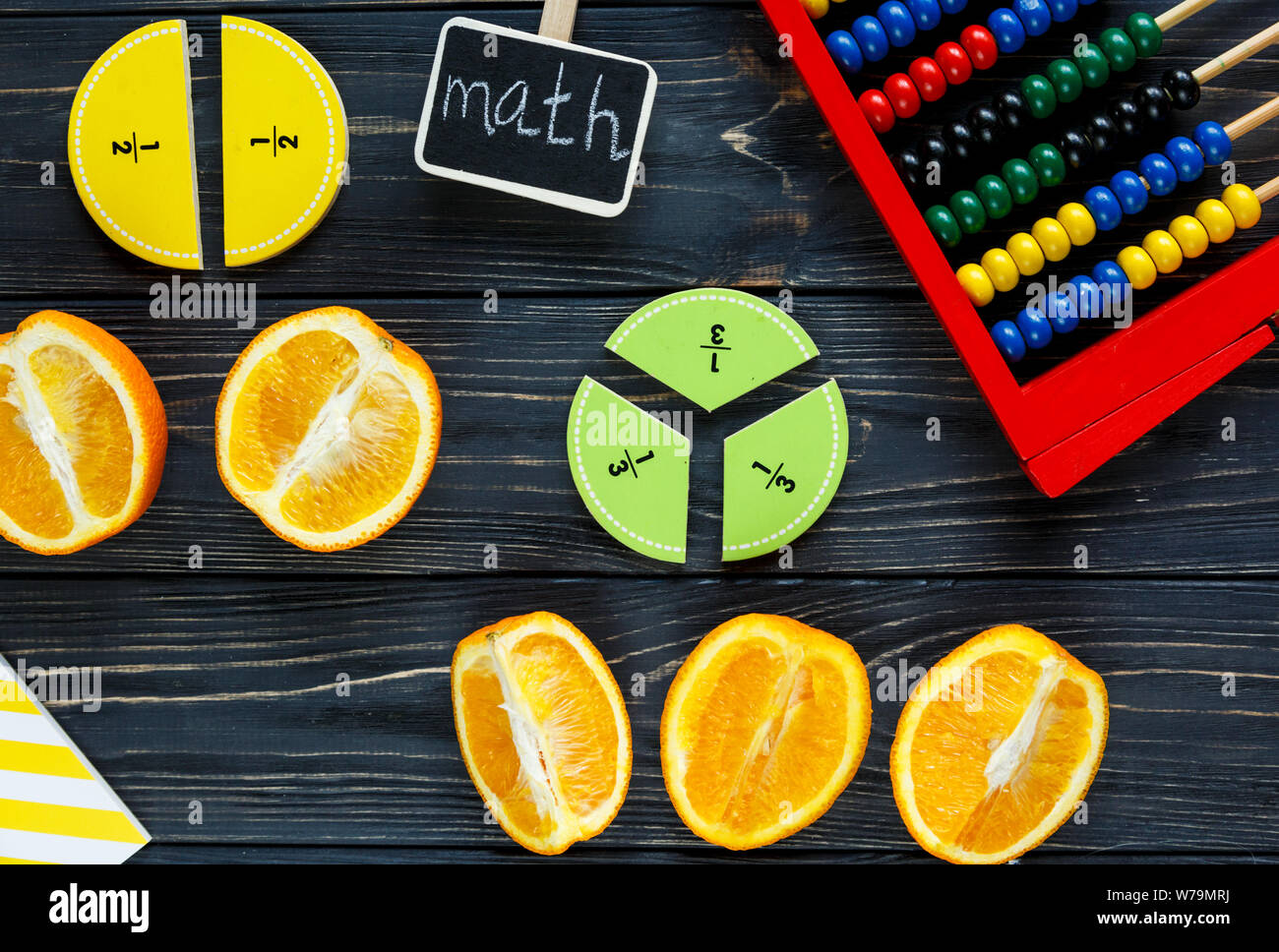 Сolorful math fractions and oranges as a sample on dark wooden ...