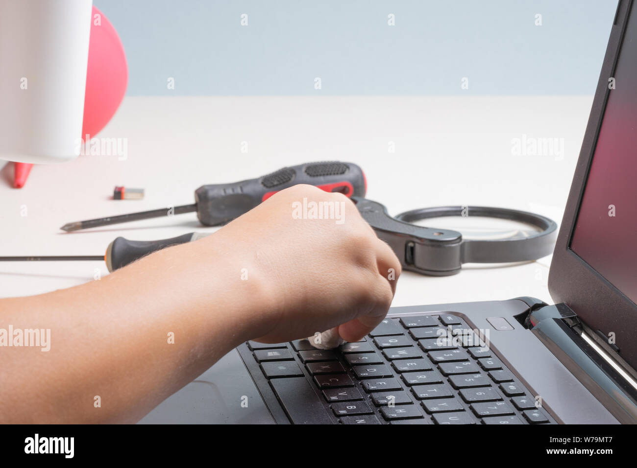 A teenager boy of 10 years old is cleaning his laptop with a special ...