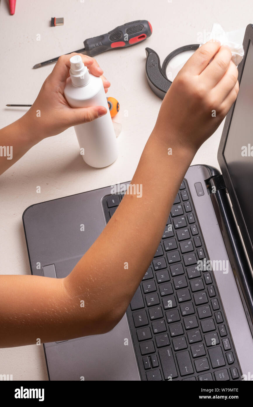 A teenager boy of 10 years old is cleaning his laptop with a special ...