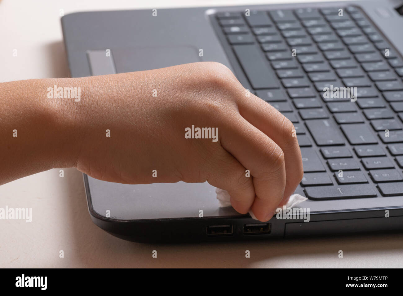 A teenager boy of 10 years old is cleaning his laptop with a special ...