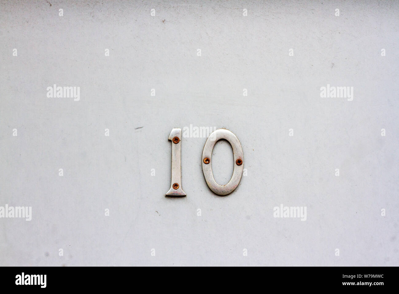 House number 10 with the ten in silver metal digits on a white surface ...