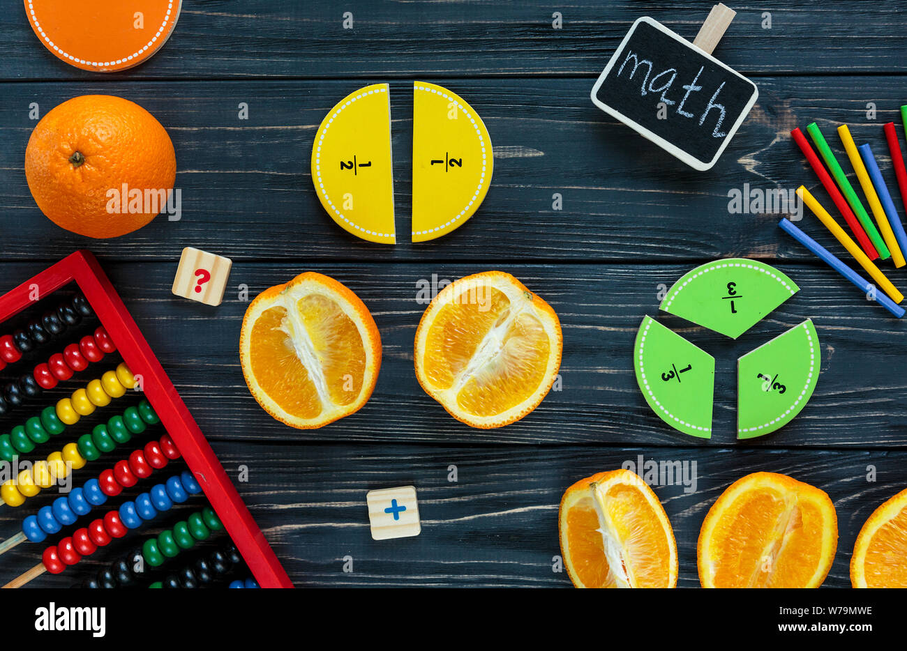Сolorful math fractions and oranges as a sample on dark wooden ...