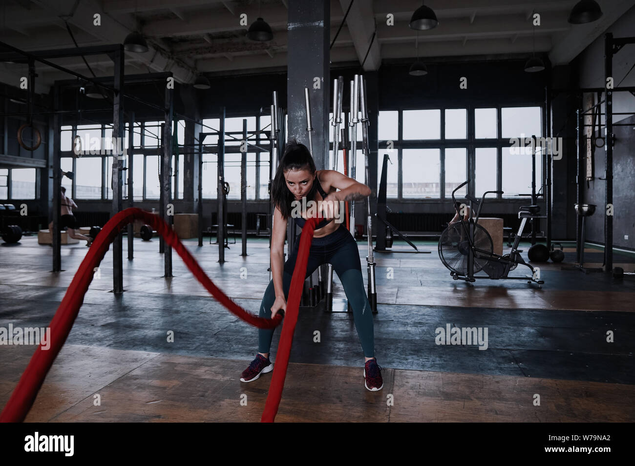 Fit woman using battle ropes during strength training at the gym ...