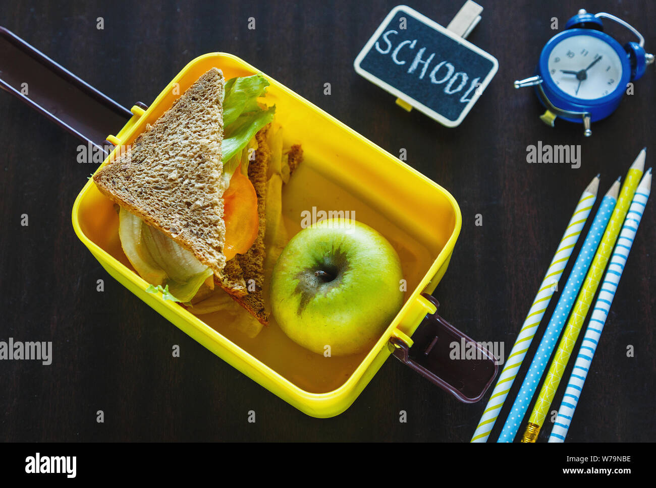 School yellow lunch box with sandwich, green apple, clock on chalkboard ...