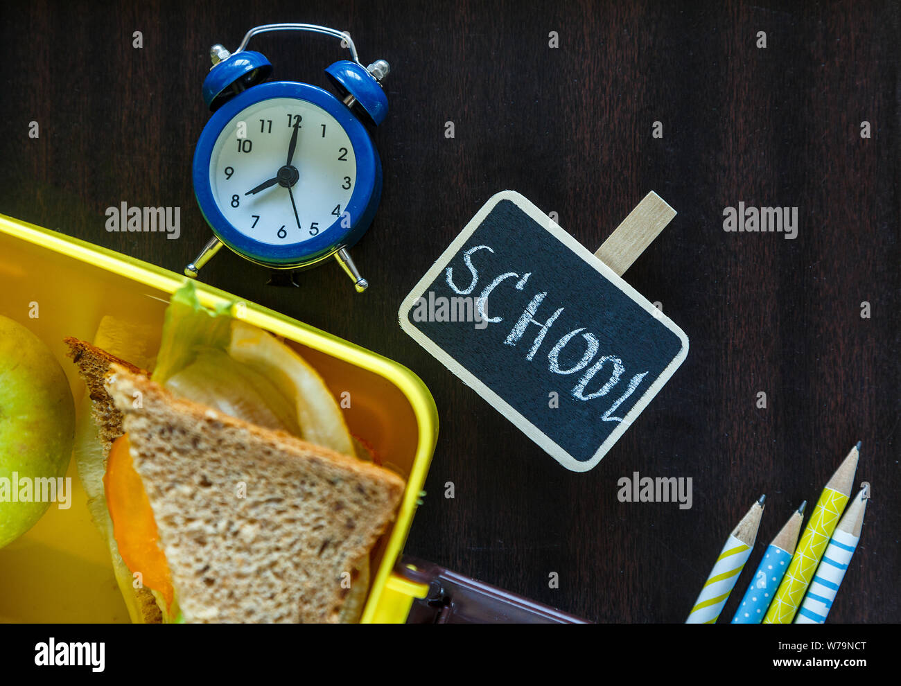 School yellow lunch box with sandwich, green apple, clock on chalkboard ...