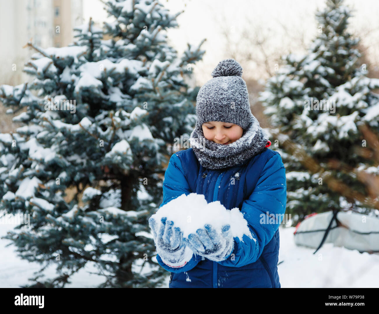 Happy cute excited boy teenager plays with snow, makes snowballs ...