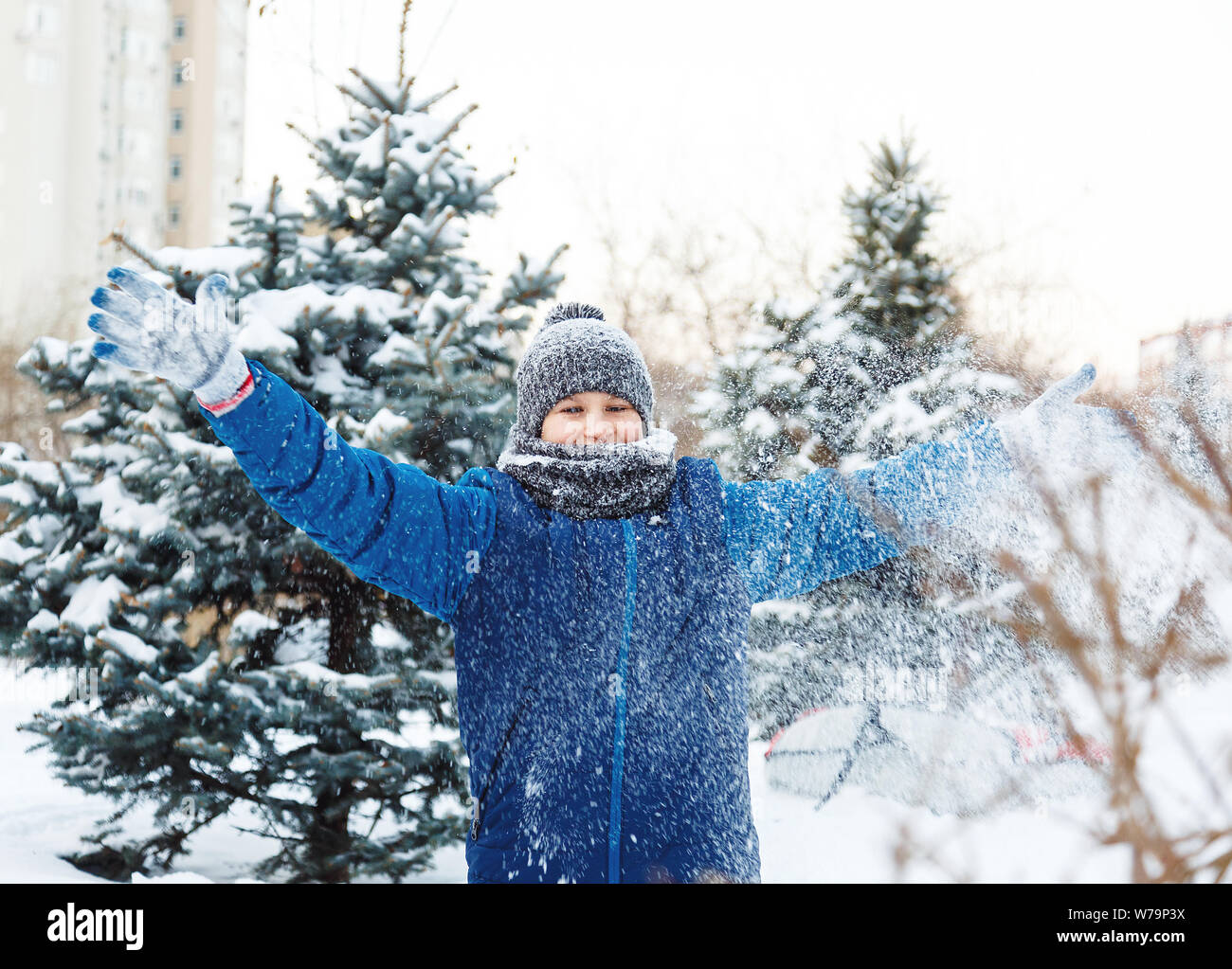 Happy cute excited boy teenager plays with snow, makes snowballs ...