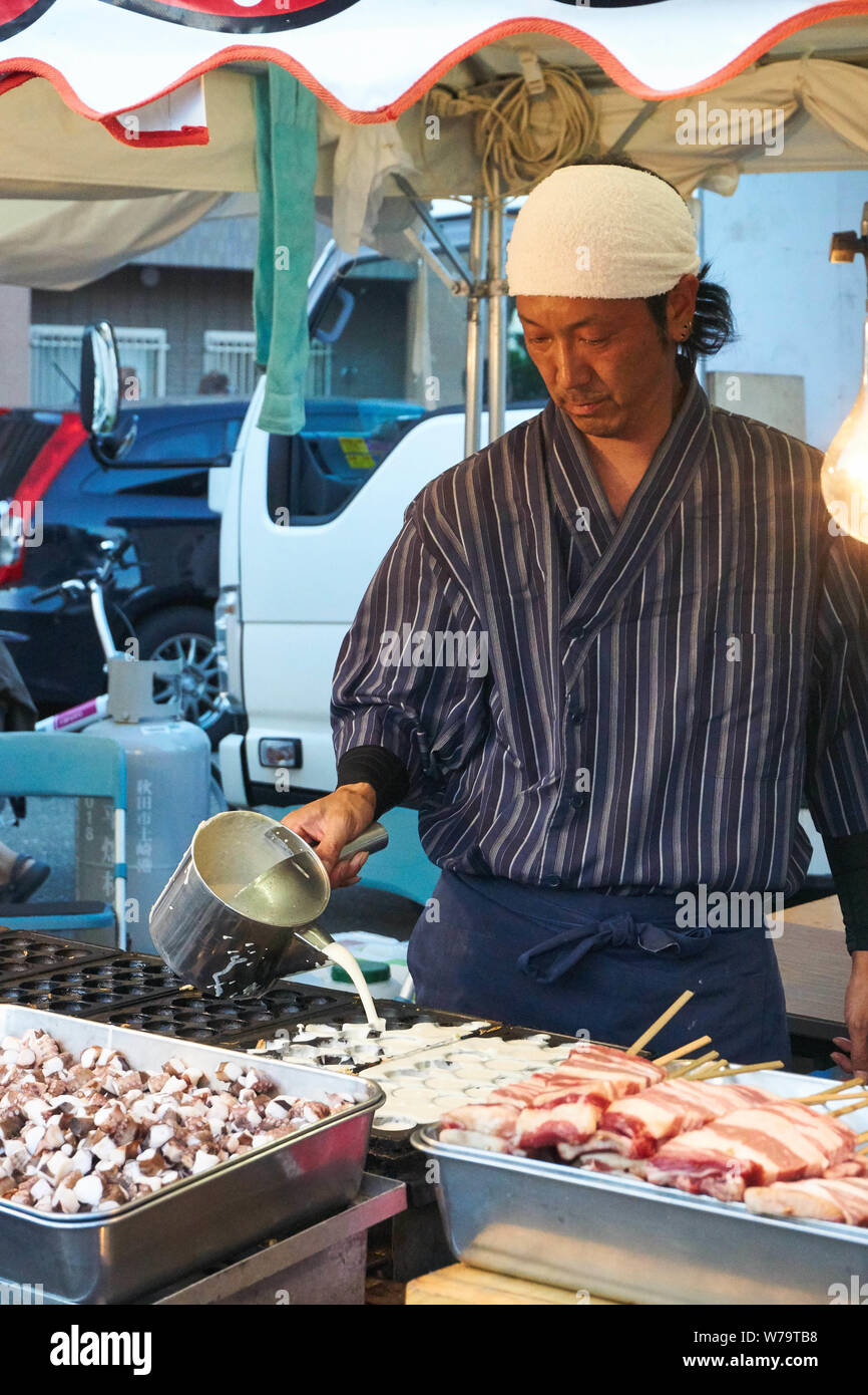 A Japanese man at a food stall pours batter to make takoyaki (octopus ...