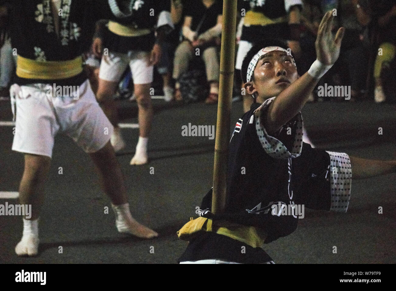 A Japanese man balances a bamboo pole on his hip during traditional ...