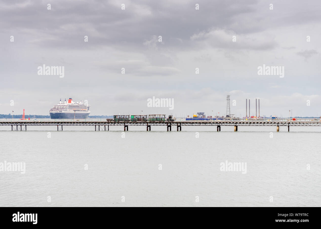Hythe Pier on a cloudy grey day with the Queen Mary 2 leaving the Port ...