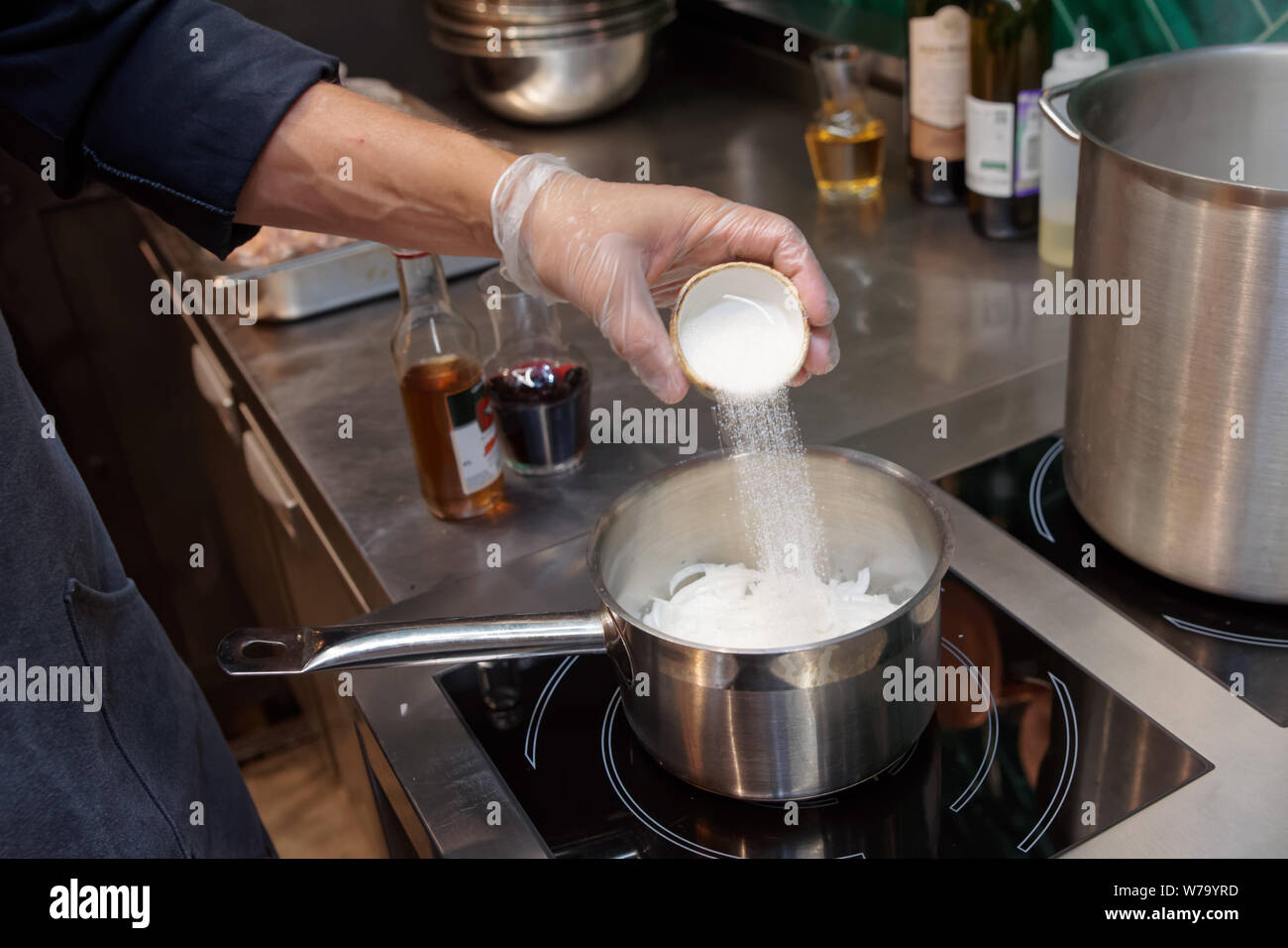 Chef is adding sugar to the pan in commercial kitchen Stock Photo - Alamy