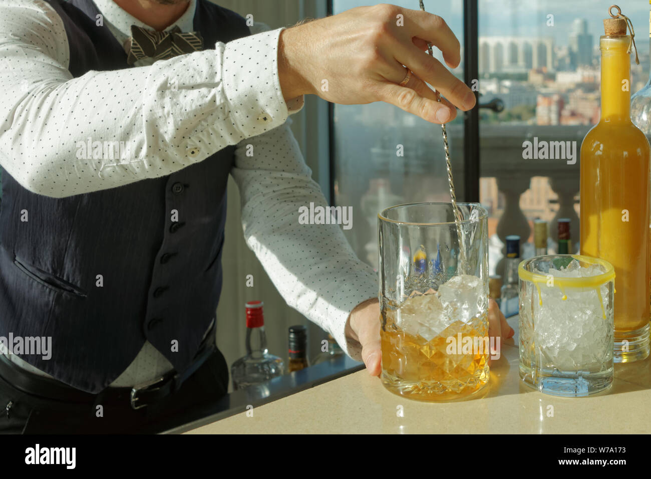 Bartender is stirring cocktail with ice cubes in mixing glass Stock Photo - Alamy