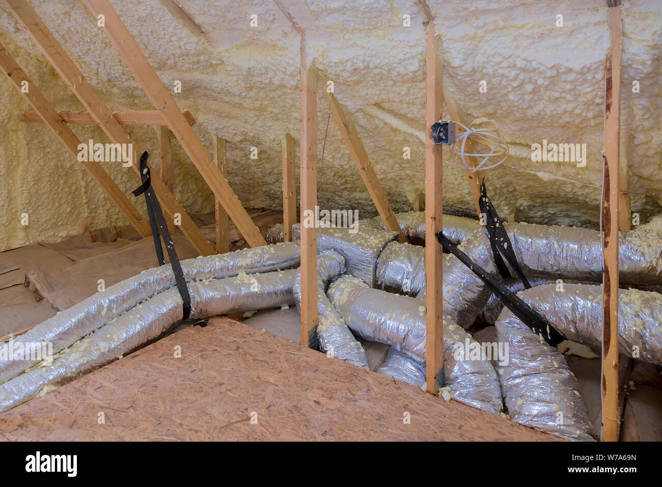 House air ventilation pipes in silver insulation material on the attic with a heating system ...