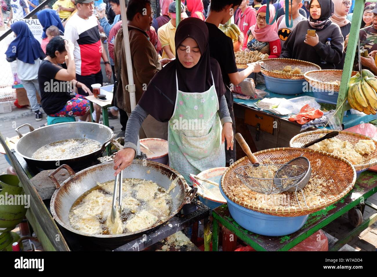 Jakarta, Indonesia - August 2019 : A muslim woman are frying bananas ...