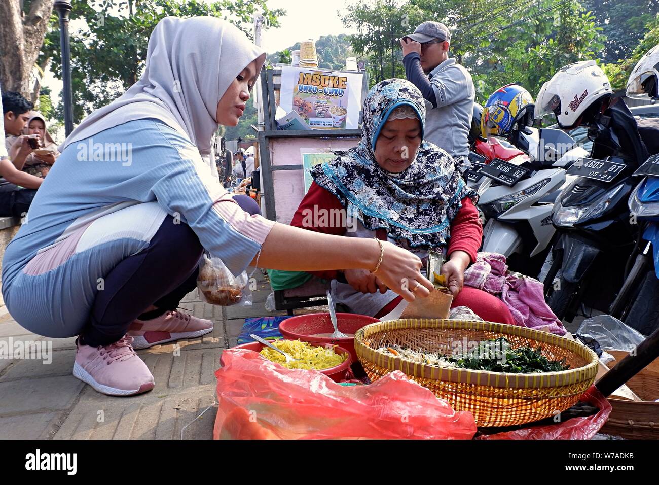 A woman street food entrepreneur and her customer on the street side ...