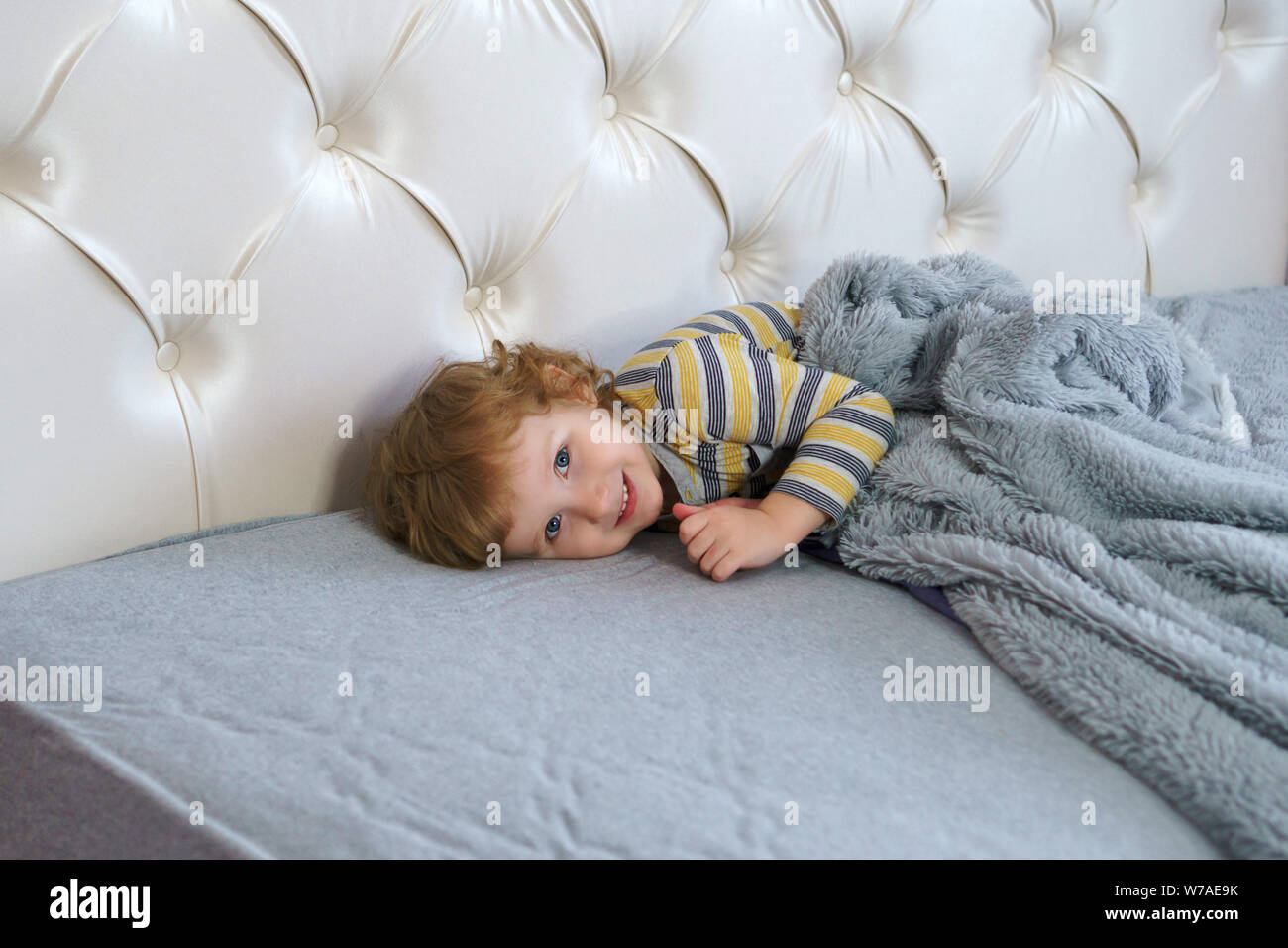 Portrait of a charming baby with golden hair and clear blue eyes. Angel ...