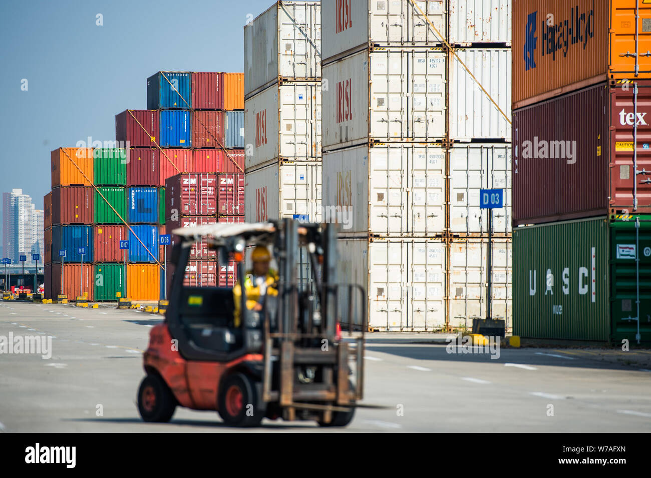 A vehicle drives past containers to be shipping abroad piled up in the ...