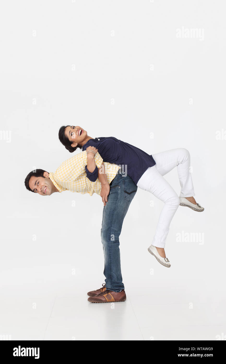 Young man carrying back to back his girlfriend isolated on white ...