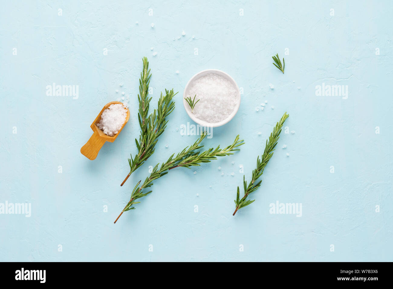Coarse sea salt and fresh rosemary twigs on light blue background ...