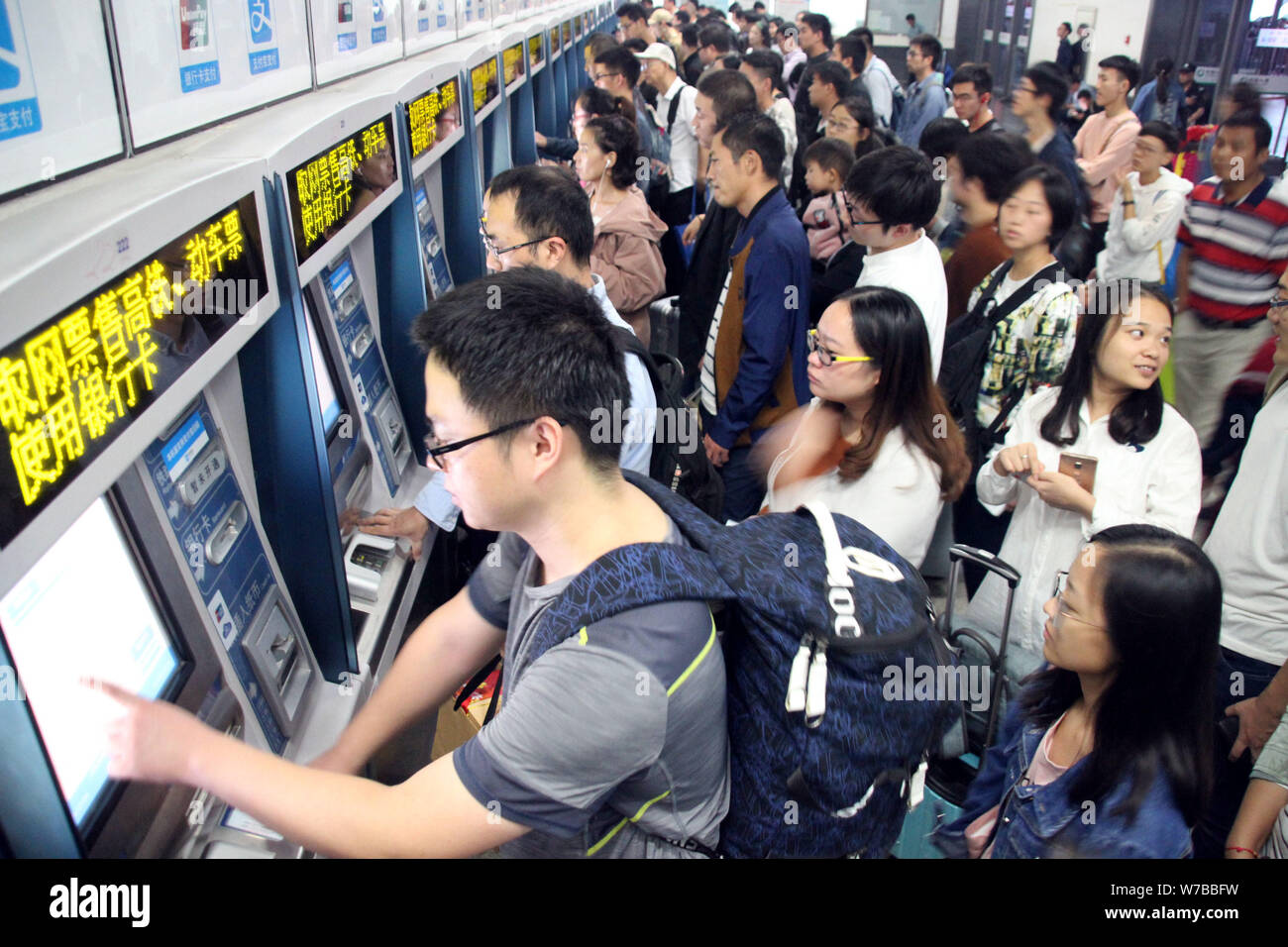 Chinese passengers queue up to buy tickets at the Suzhou Railway ...