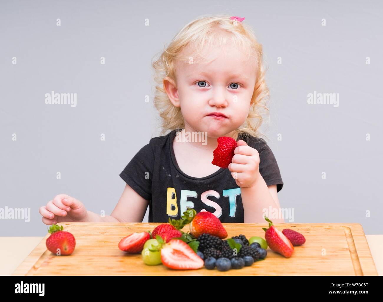 Happy kid eating fresh strawberries Stock Photo - Alamy