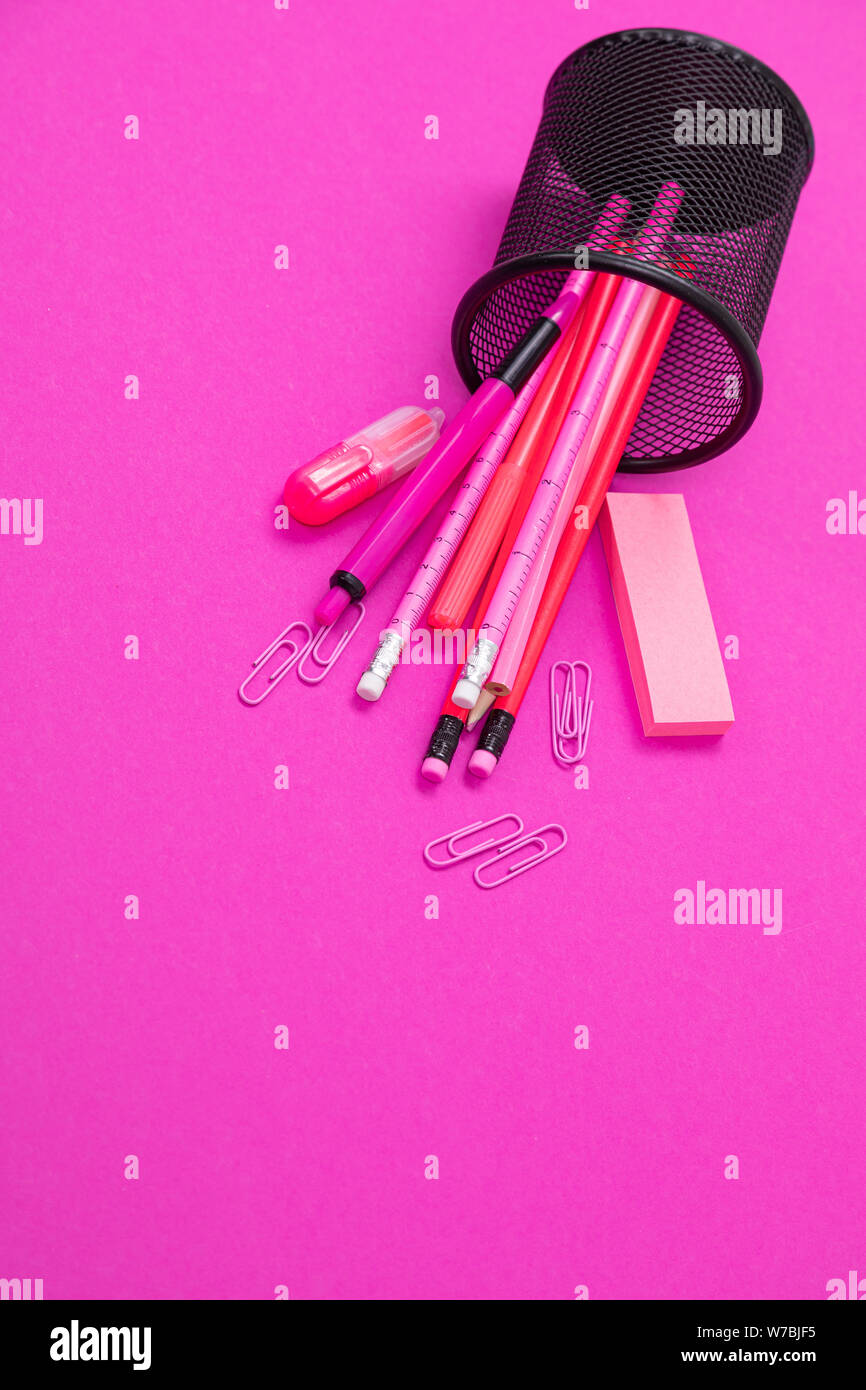 Group of pink color stationery products are scattered from pencil bin ...