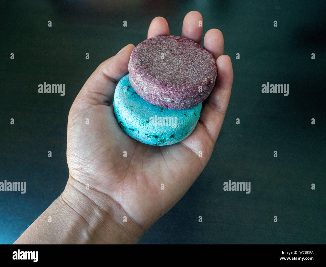 Hand Holding two red and blue Shampoo bars before washing their hair in ...