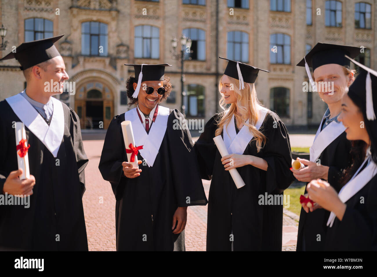 Smiling graduates congratulating each other before leaving Stock Photo ...