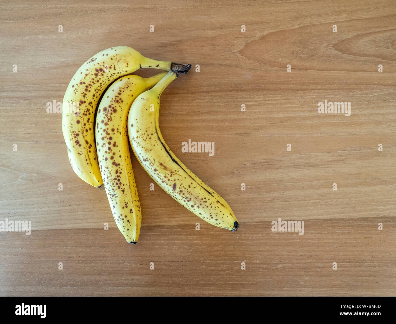 Overripe bunch of medium sized bananas isolated on a hardwood ...