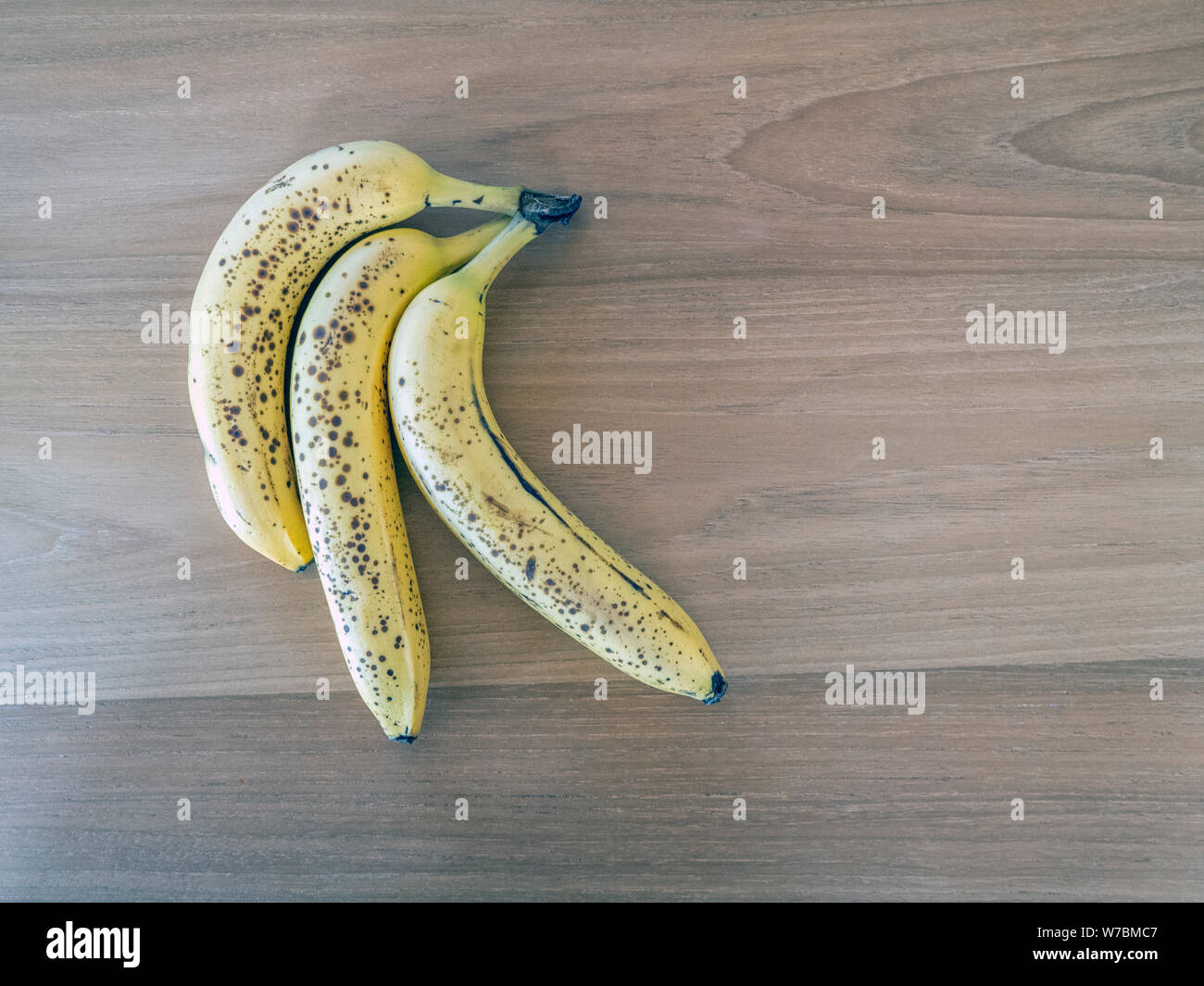 Overripe bunch of medium sized bananas isolated on a hardwood ...