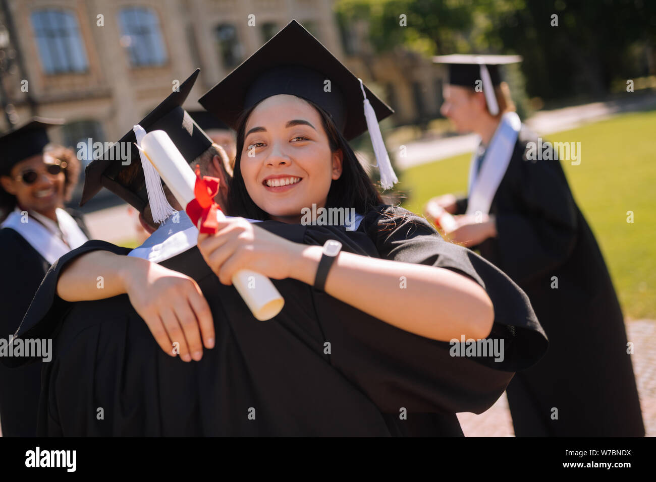 Smiling girl hugging her groupmate after graduation Stock Photo - Alamy