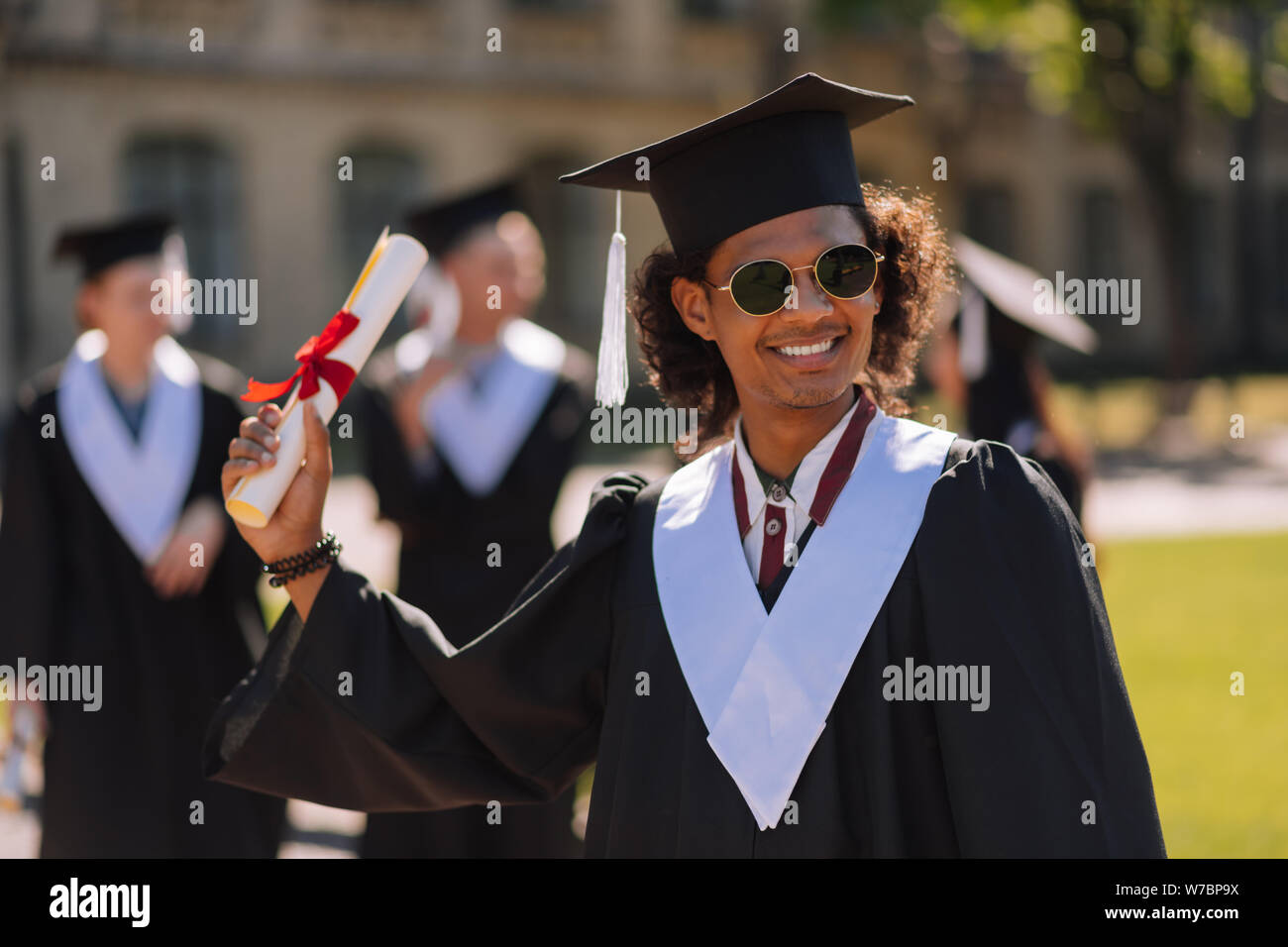 Cheerful graduant raising hand with his diploma Stock Photo - Alamy