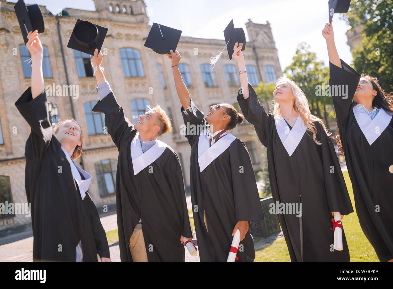 Happy students raising their masters caps together Stock Photo - Alamy