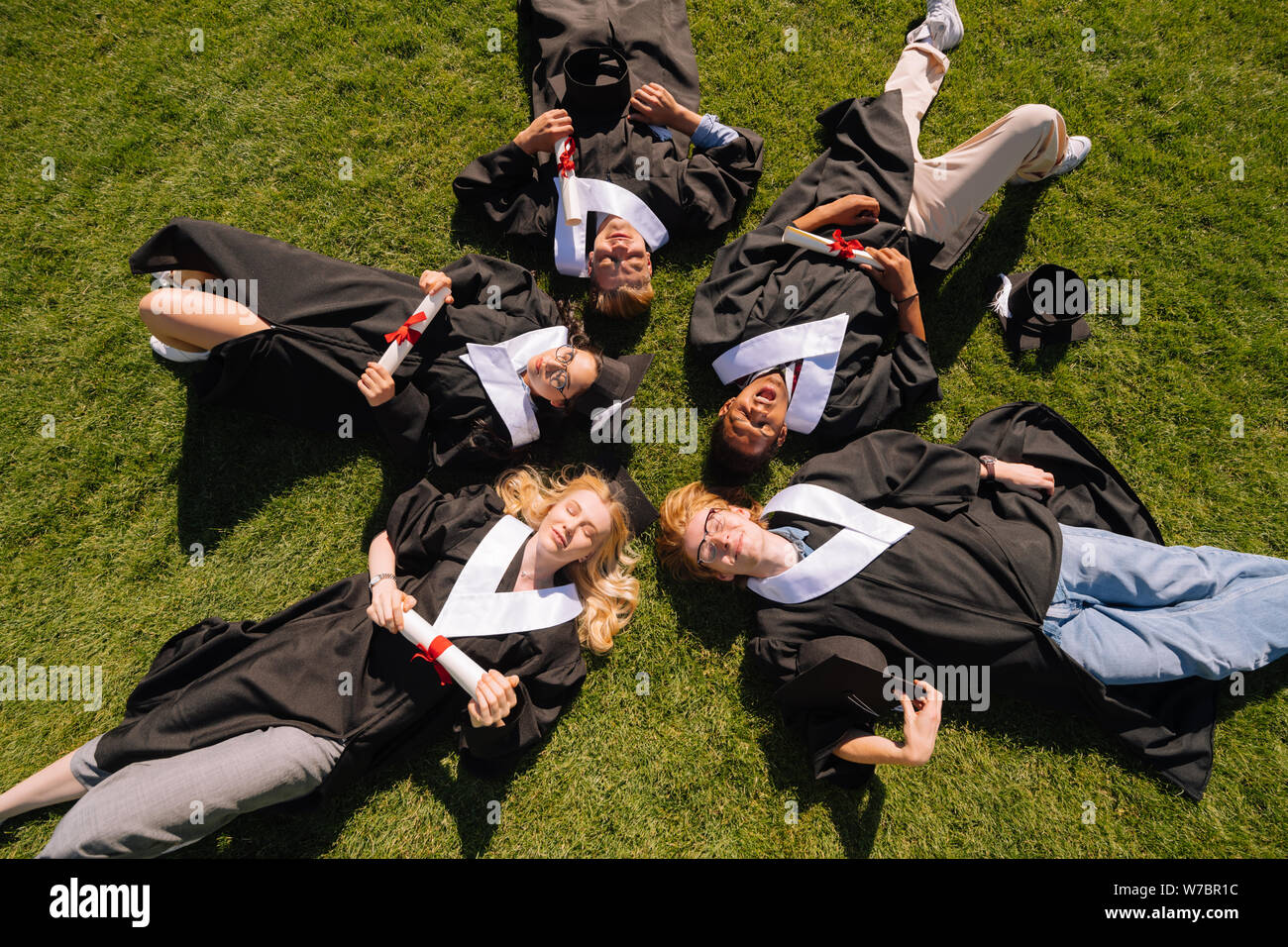 Graduates lying together on the grass lawn Stock Photo - Alamy