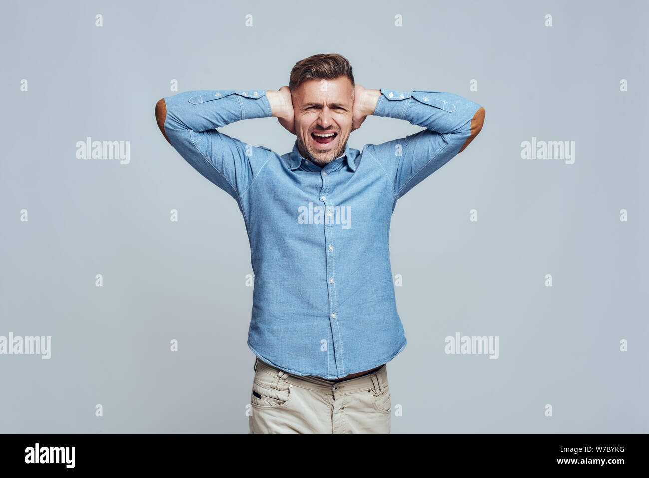 Bla bla bla. Depressed man closing ears with both hands and screaming ...