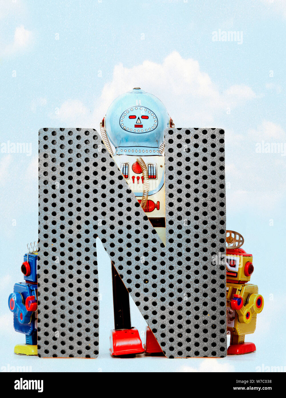 retro robots holding a big metal letter N with blue sky and clouds ...