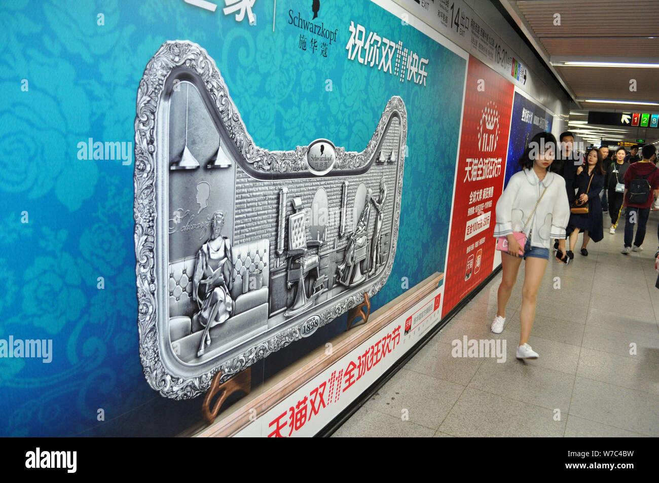 Pedestrians walk past advertisements for the Tmall 11.11 online shopping festival on the Singles ...
