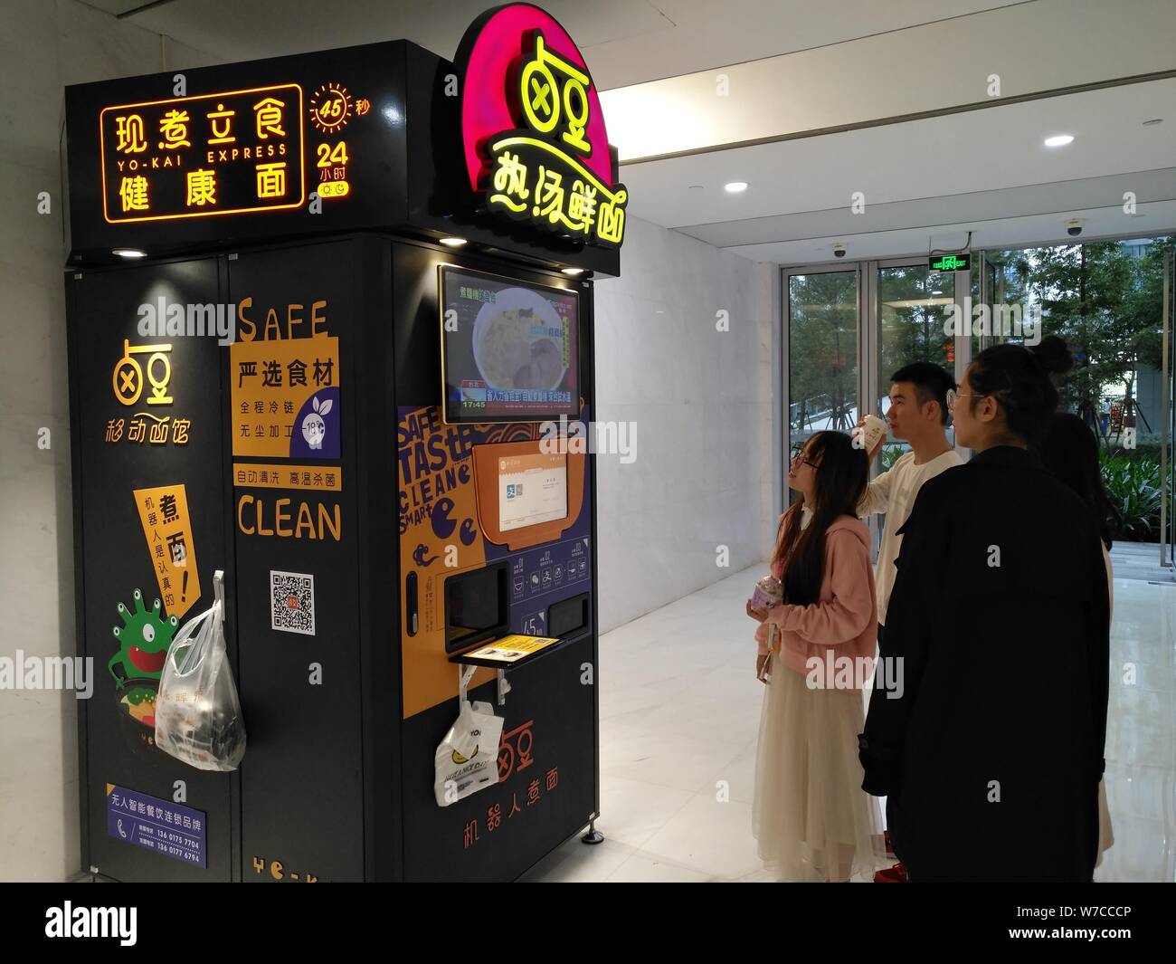 Chinese white-collar workers look at a mobile self-service noodle shop ...