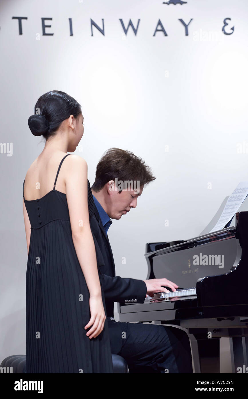 Chinese pianist Li Yundi instructs an enthusiast to play the piano at ...